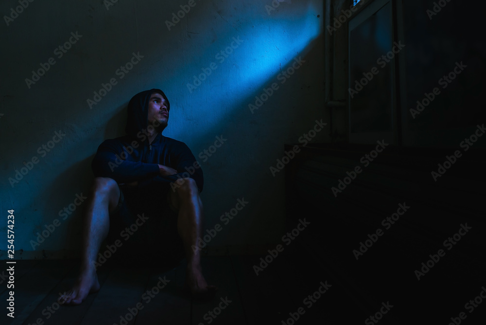 Sad and lonely man sitting in the dark room ,Depressed young man ...