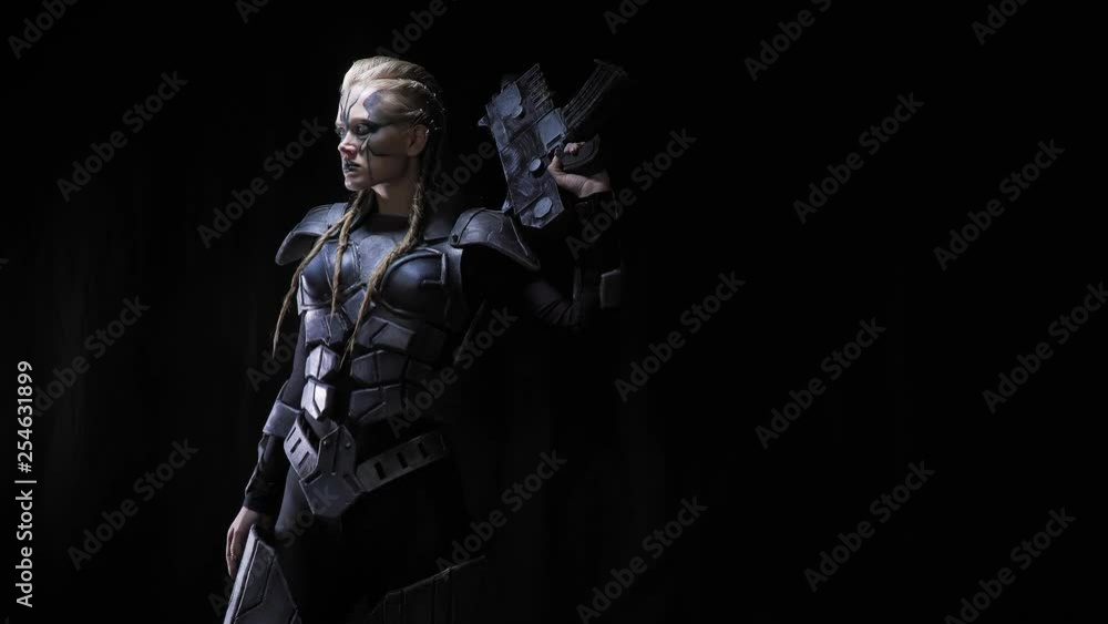 Scary alien female in full body armor is putting a gun on her shoulder ...