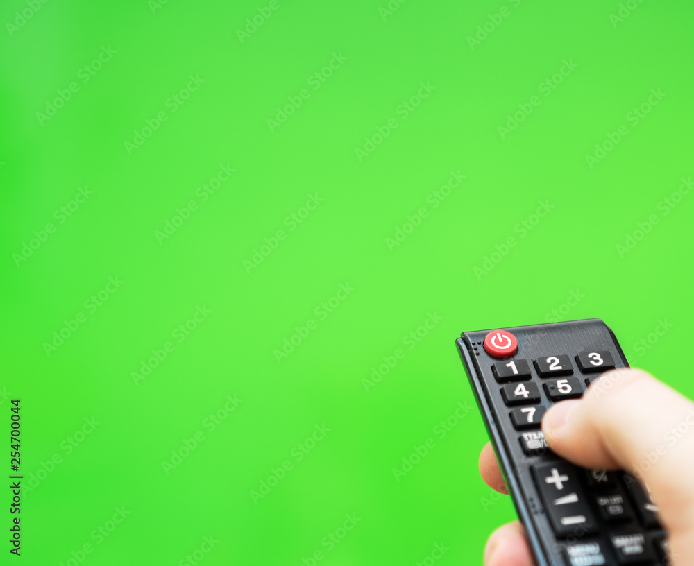Male hand with TV remote control over green screen. Place for your ...