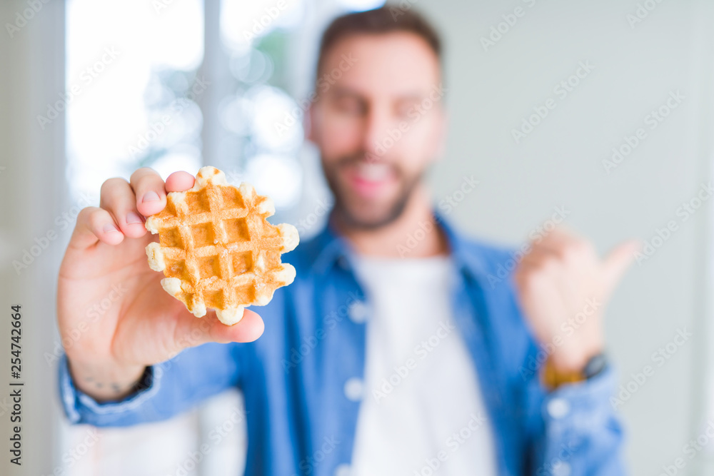 Handsome man eating sweet Belgian pancakes pointing and showing with ...