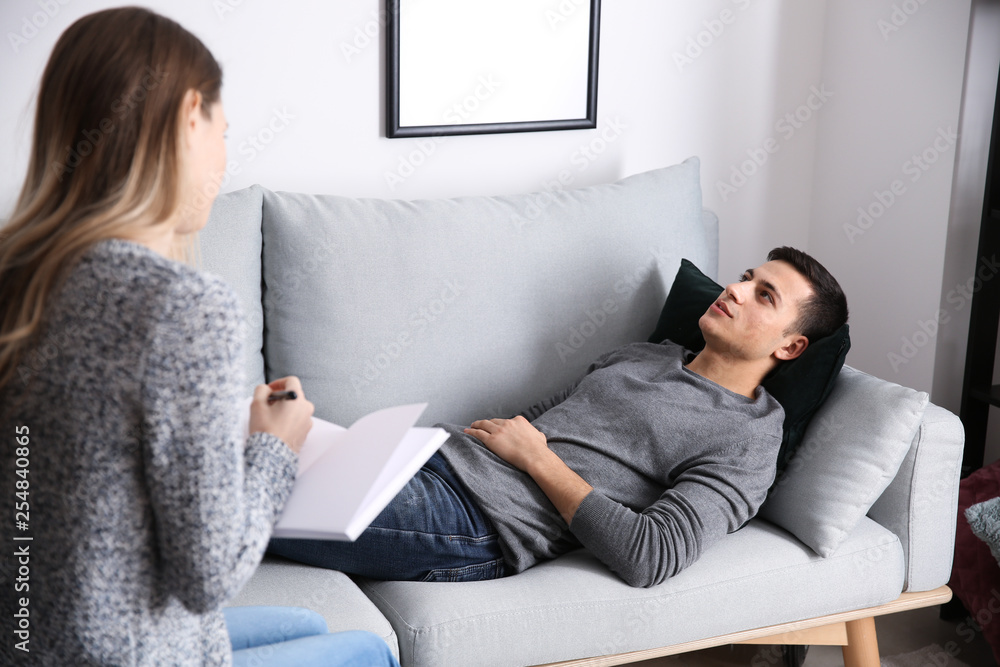 Female psychologist working with patient lying on sofa in her office ...