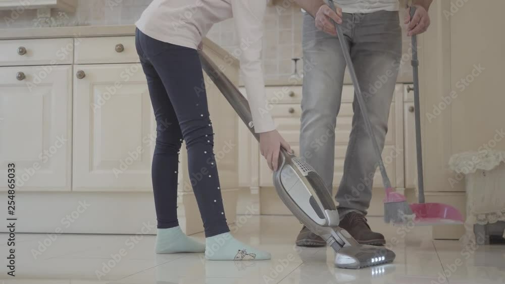 Dad and daughter having fun in a clean house. A man with broom and ...