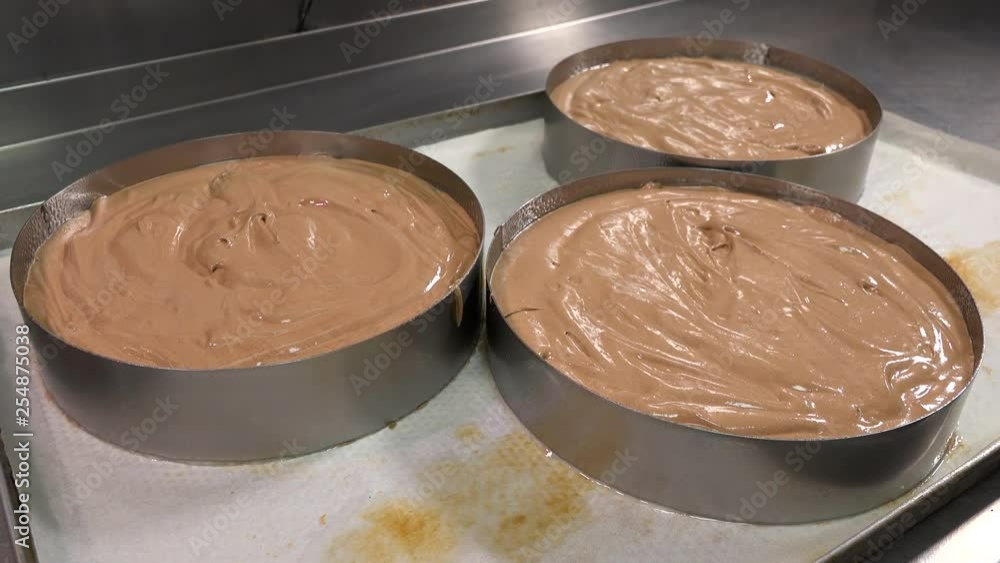 Three cake forms with brown dough inside on a kitchen counter - closeup ...