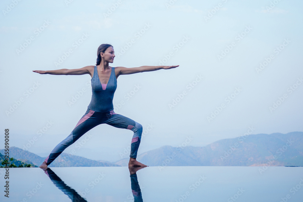 Beautiful woman practice yoga pose on the infinity pool above the ...