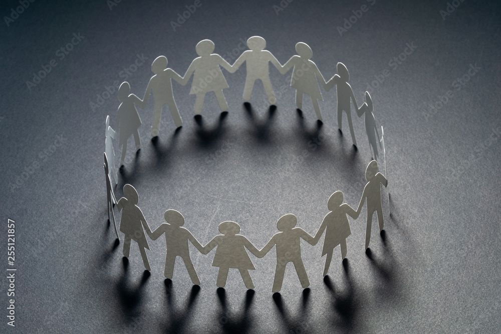 Circle of paper people holding hands on dark surface. Community ...