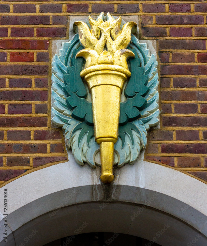 Golden torch with flames carved in stone with a bright green background ...