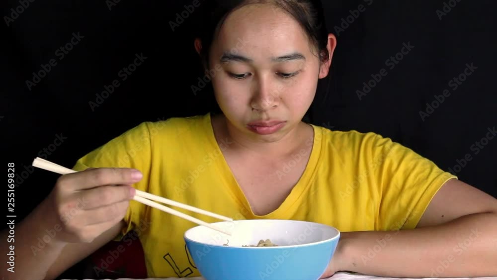 Asian girl bored of eating instant noodles, black background. Junk food ...