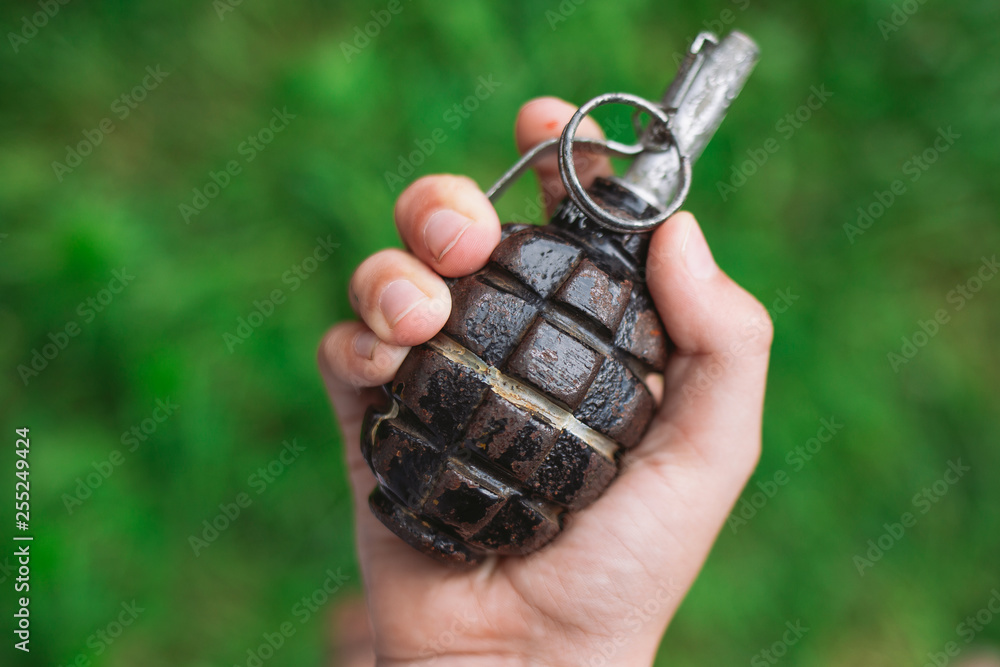 Closeup top view of white kid hand holding real old grenade. Horizontal ...