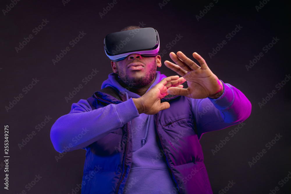 Young dark-skinned man dressed in outdoor wear having on head mobile ...