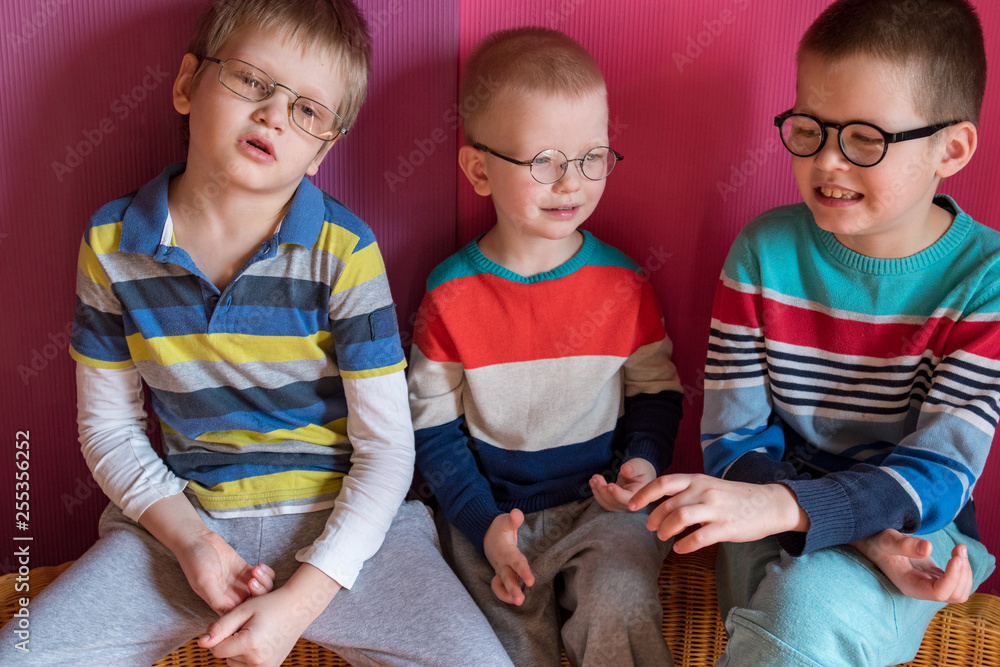 Three brothers in bright colored clothes posing in front of camera with ...