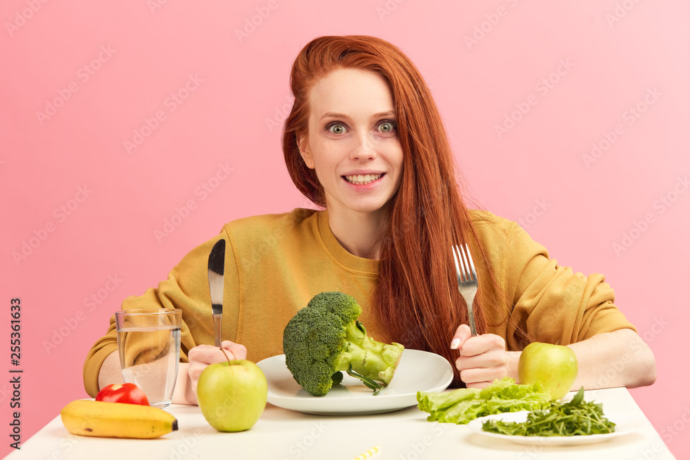 Hungry young vegg woman eating with eagerness and appetite raw green ...