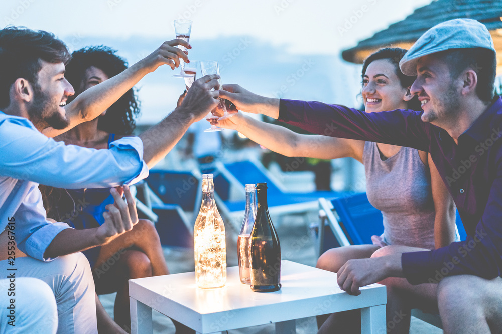 Group of young tourist friends cheering with champagne at beach party ...