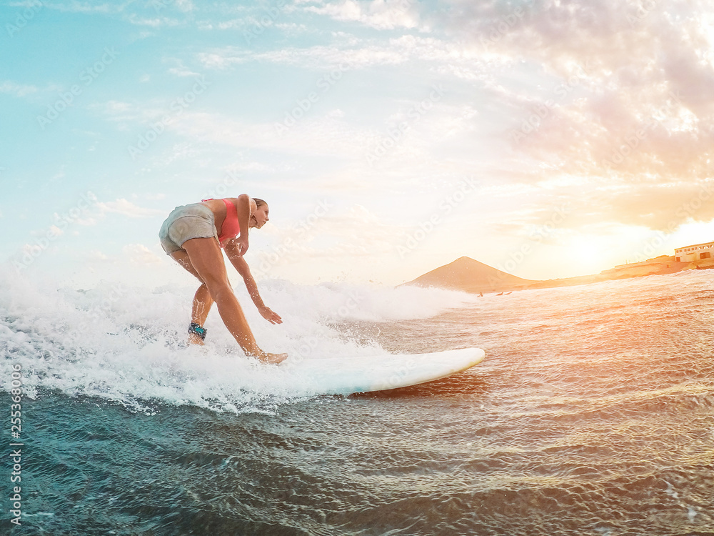 Female athlete surfing at sunset - Surfer woman performing outdoor ...