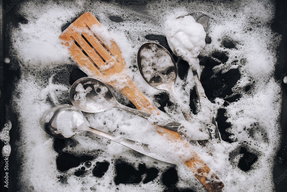 Washing dishes concept. A still knife, wooden kitchen spatulas and ...