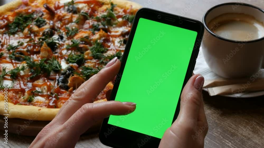 Chroma key or green screen on a black smartphone in female hands with a ...