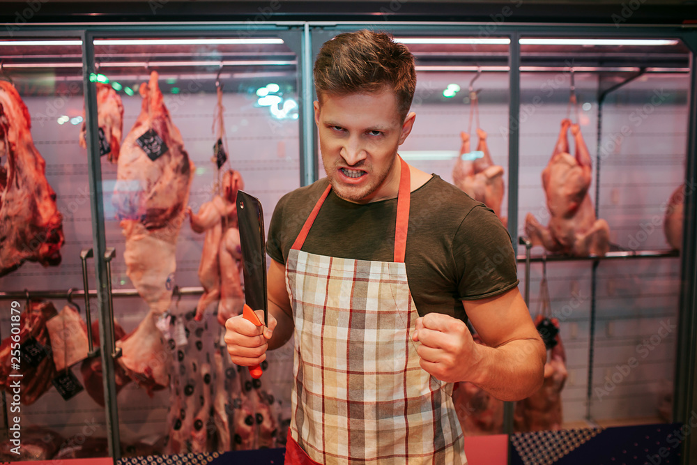 Young angry man stand in front of meet shelf in grocery store. He hold ...