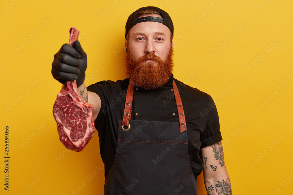 Look, its delicious. Self confident male butcher holds raw ribeye steak ...