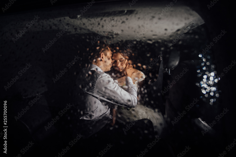 The bride and groom kissing in the car late at night, and it's raining ...