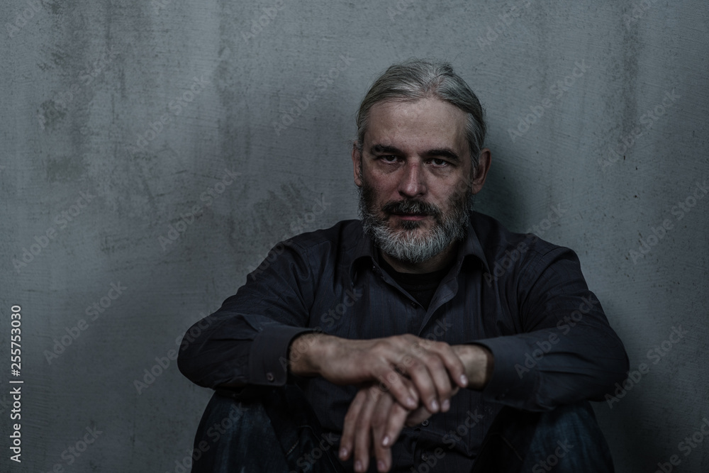 Portrait of a homeless man with a gray hair on dark background. Empty ...