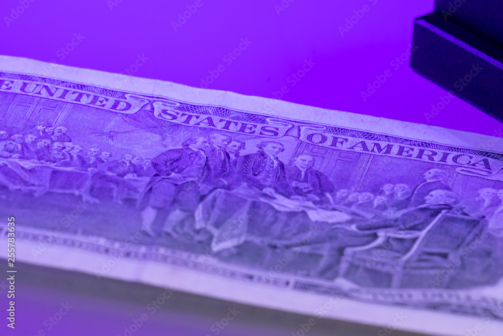Verifying the authenticity of the two-dollar bill in UV light. US ...