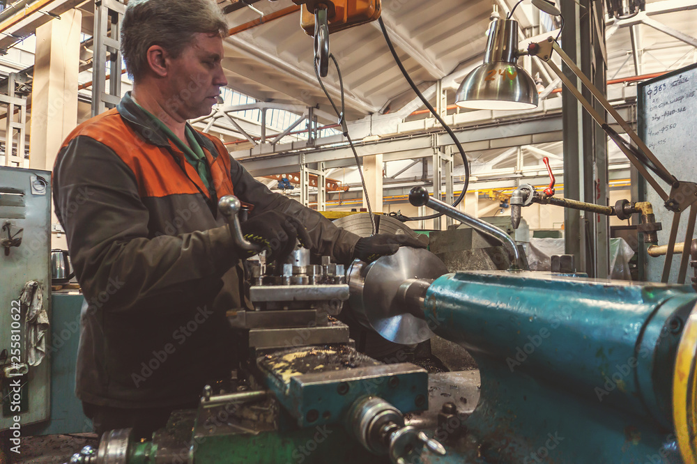 Turner worker manages the metalworking process of mechanical cutting on ...