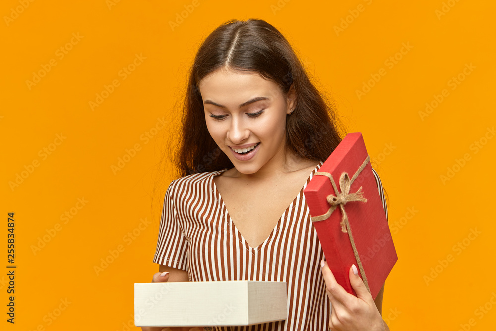 Emotional beautiful young woman with loose hair opening box with ...