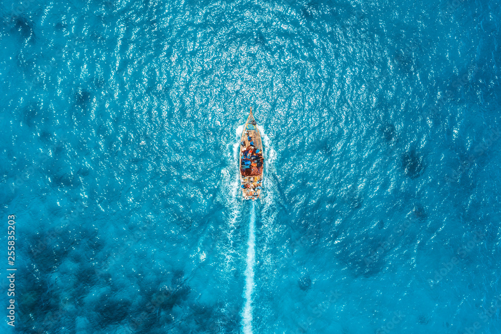 Aerial view of the fishing boat in transparent blue water at sunny day ...