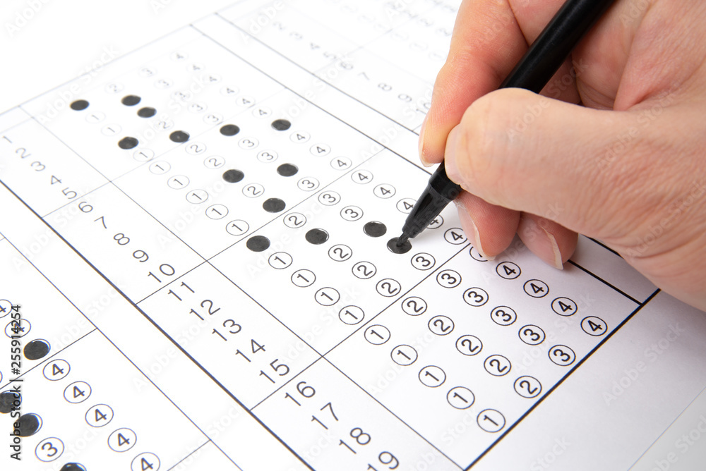 Man is filling OMR sheet handing with pen. Stock Photo | Adobe Stock
