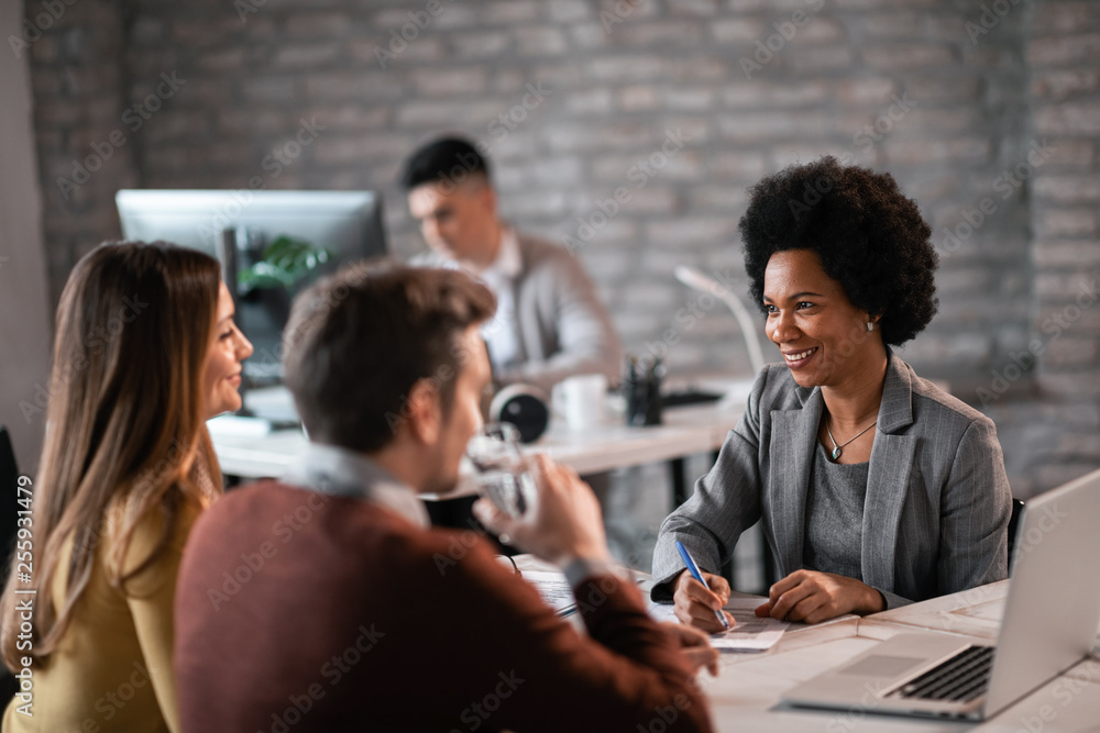 Happy African American bank manager talking with her clients on a ...