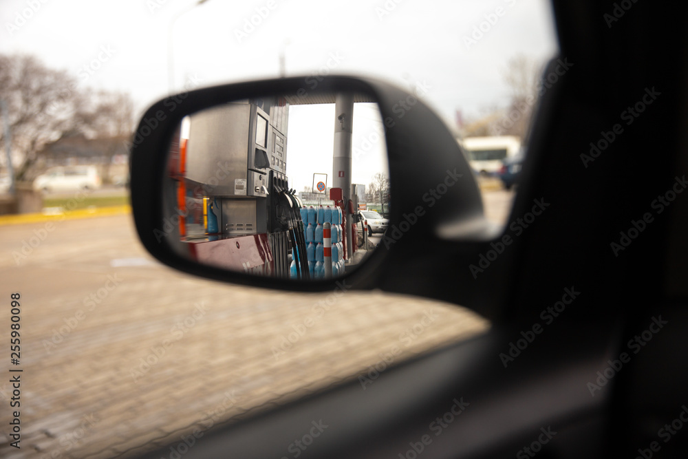 A rear window in a side car mirror during a break stop at a gas station ...