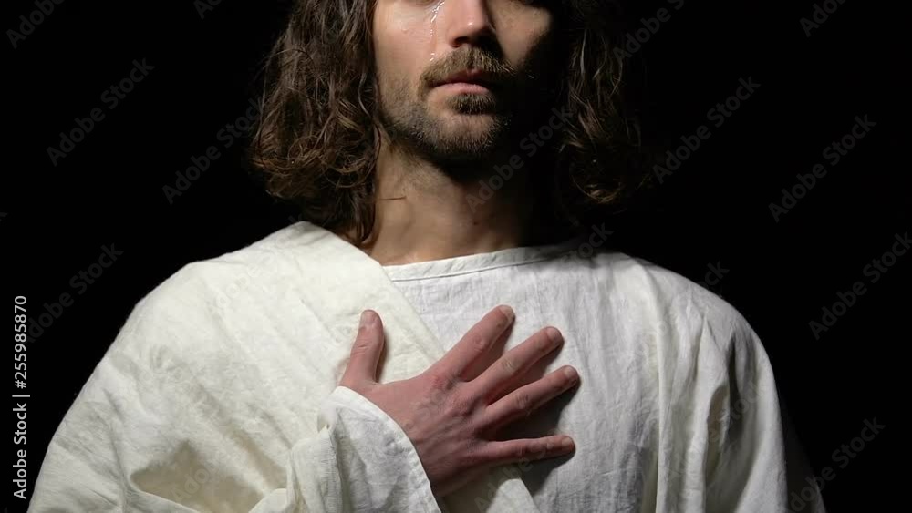 Crying Jesus Christ in crown of thorns holding hand near heart ...