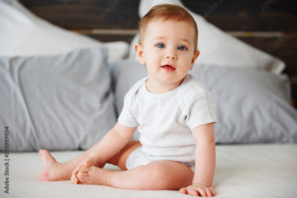 Portrait of cute baby sitting on bed Stock Photo | Adobe Stock