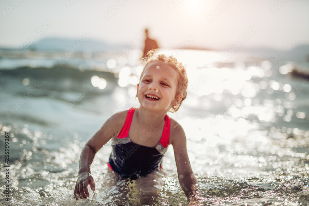 Little girl making a splash while being in the sea water soaking wet ...