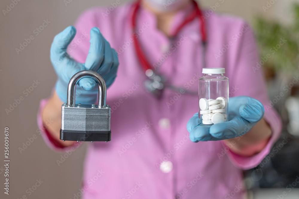 Doctor holding grey steel pad lock and giving pills bottle. Medical ...