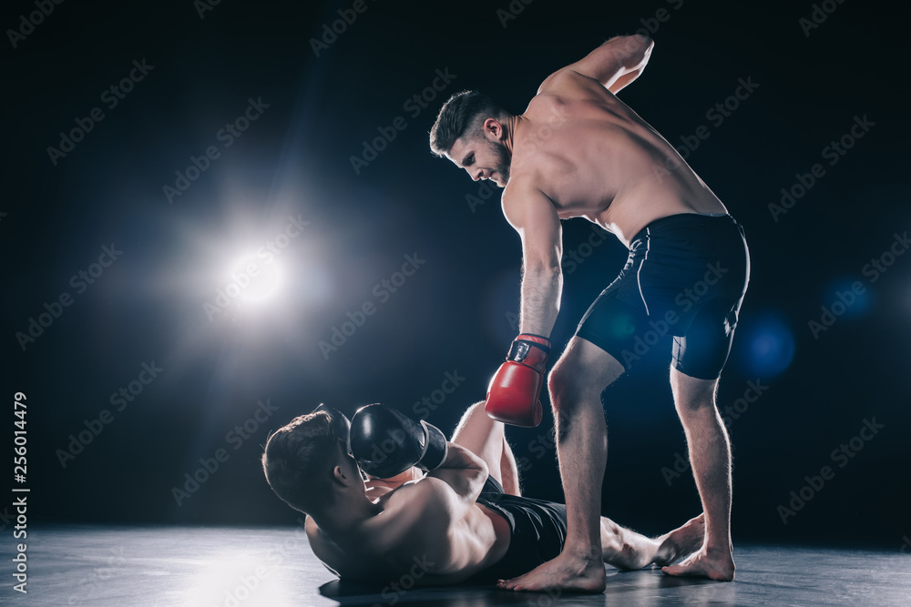 Shirtless strong mma fighter in boxing gloves standing above opponent ...
