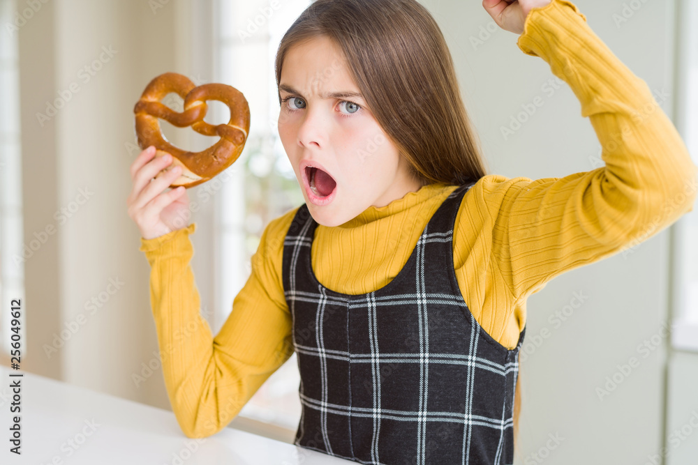 Beautiful young girl kid eating german snack salty pretzel annoyed and ...