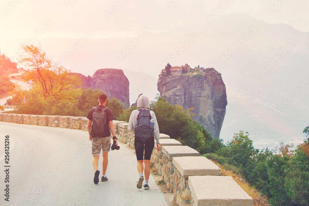 Hiking young couple tramping on asphalt road in sunset from back ...