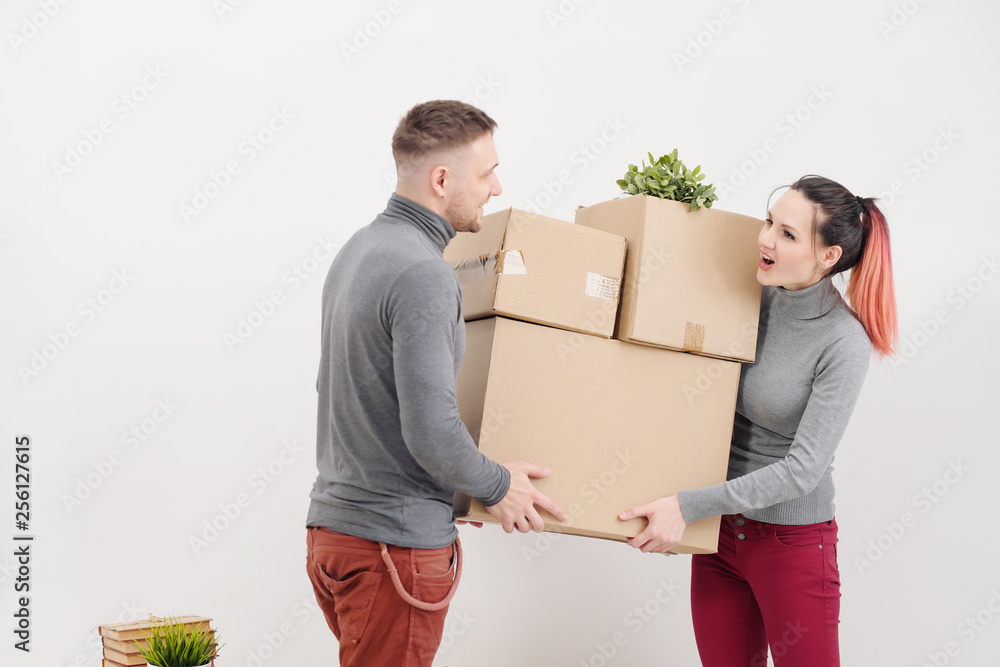 A young woman and a man carry heavy cardboard boxes with things. White ...