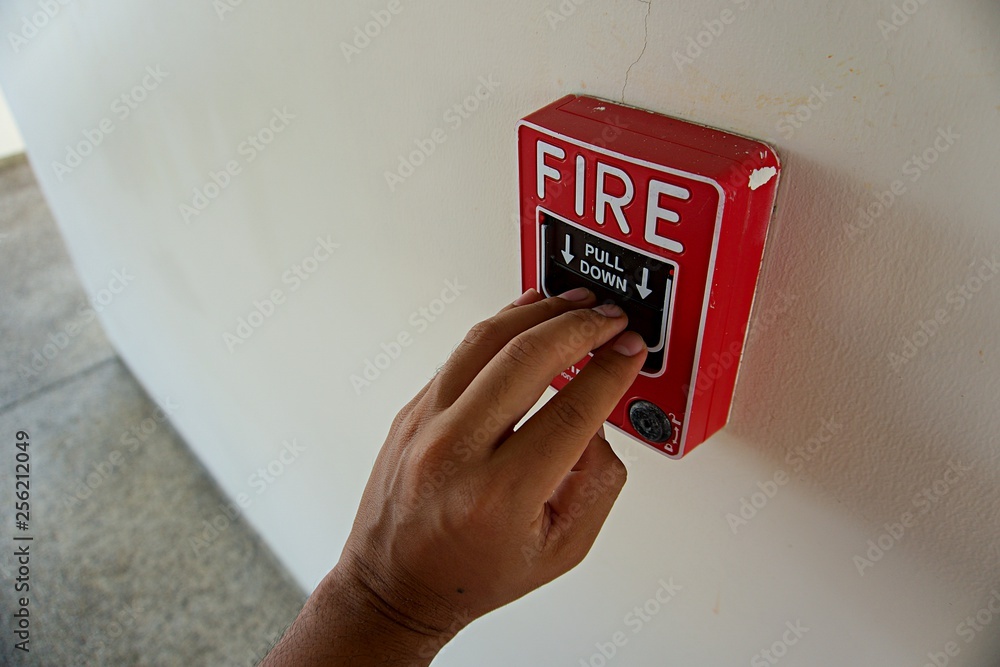 Fire alarm switch,The hand of man is pulling fire alarm on the wall ...