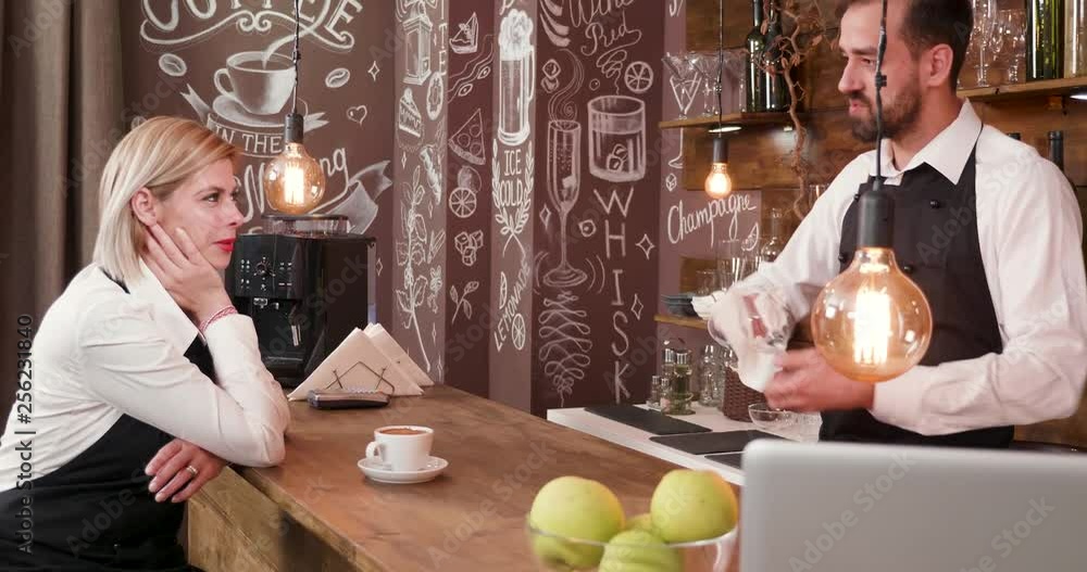 Female waitress and male waiter talking at the bar counter after work ...