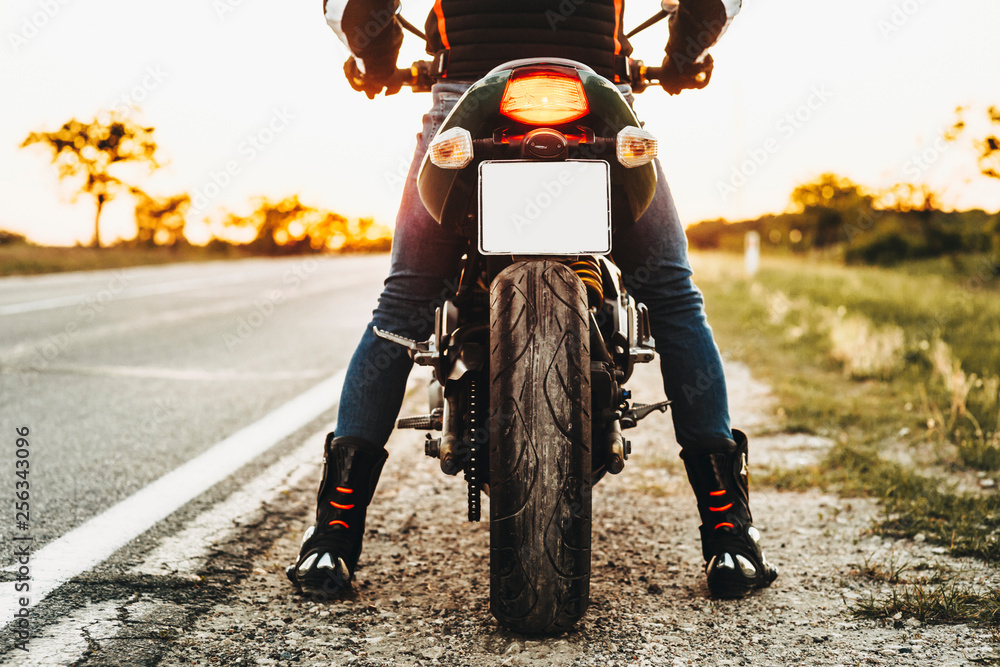 Crop of back view of a biker sitting on his motorcycle before going on ...