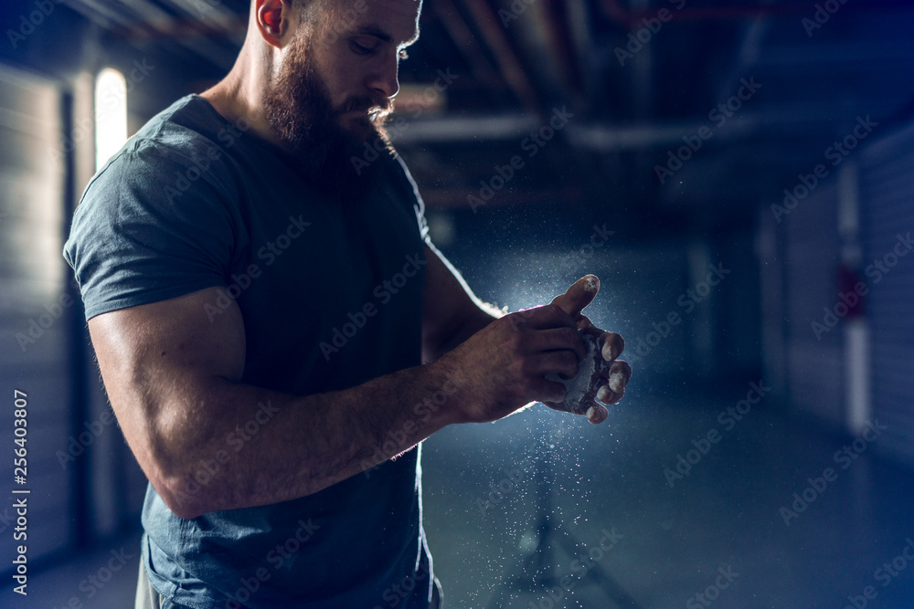 Side view of muscular bearded man clapping hands. Chalk all around ...