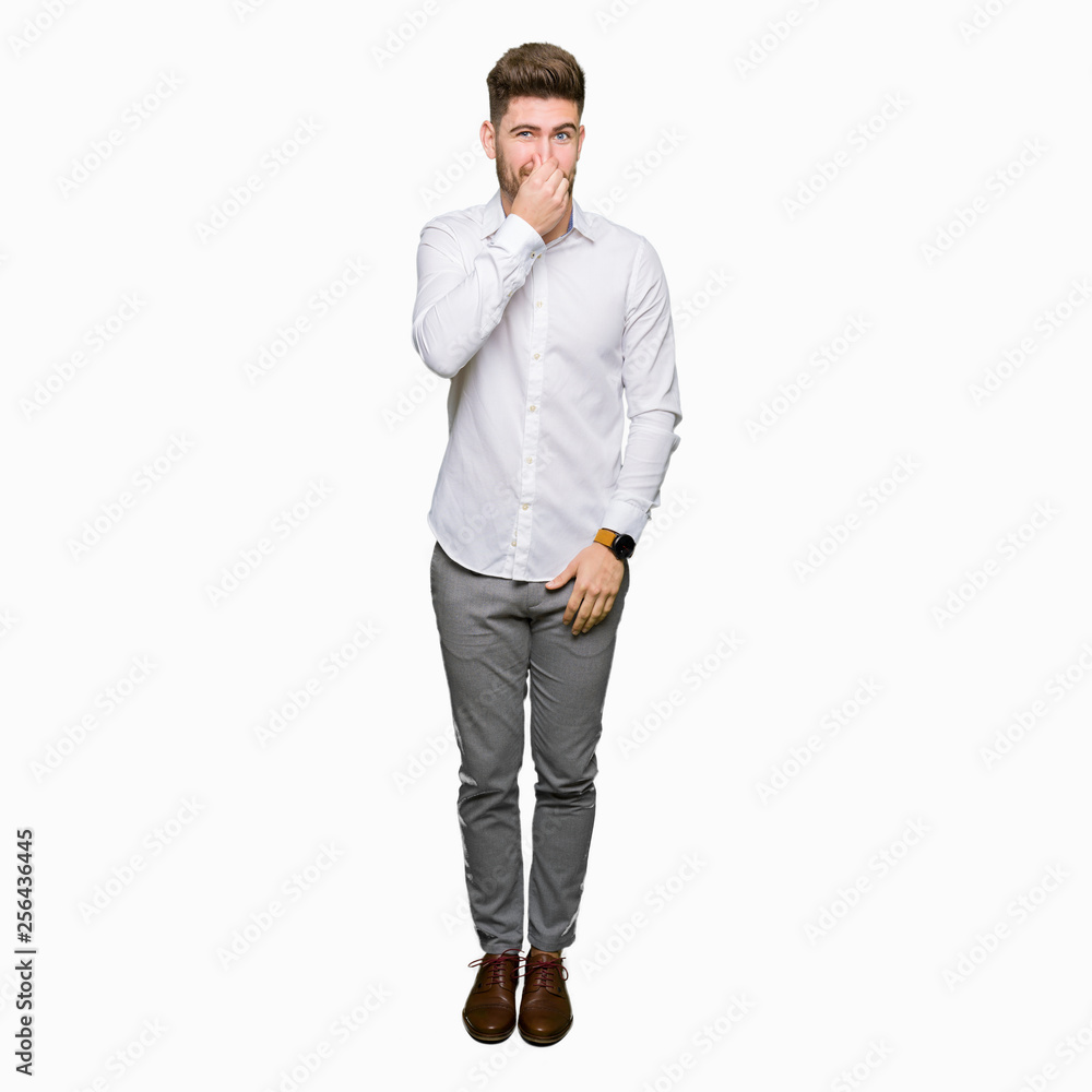 Young handsome business man smelling something stinky and disgusting ...