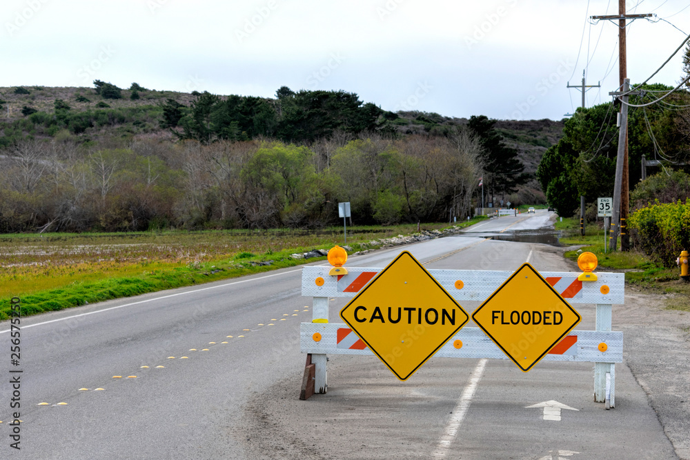 Yellow Caution and Flooded warning signs on barricade installed across ...