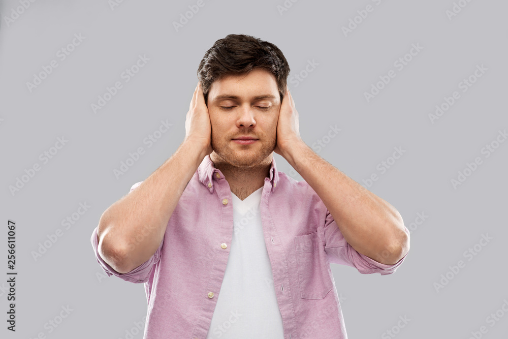 people, noise and stress concept - man closing ears by hands over grey ...