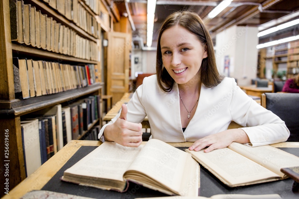 Girl reading a book in the reading room of the library shows cool ...
