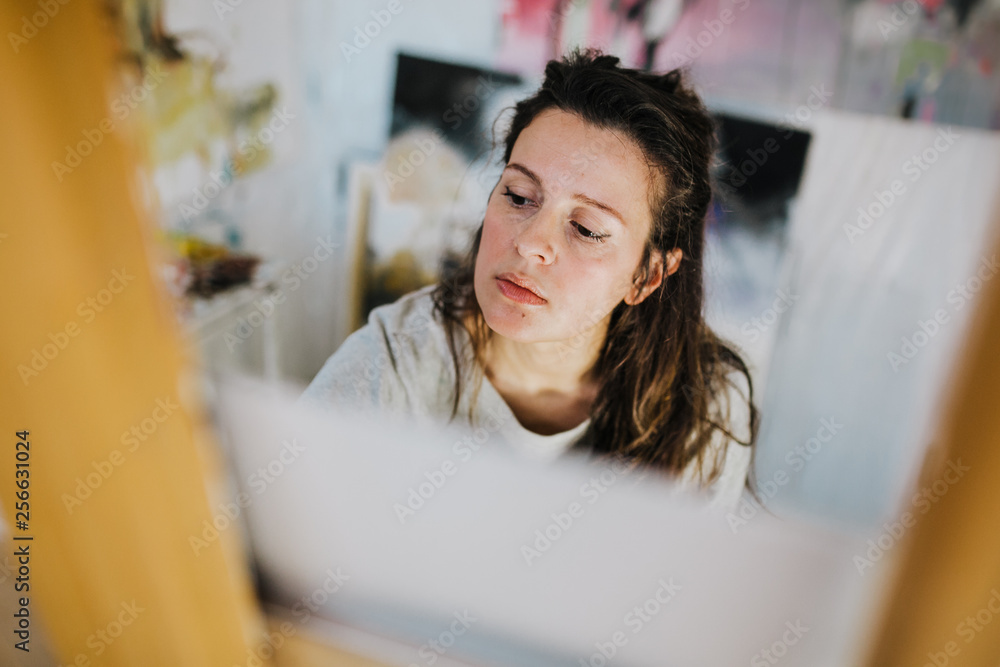 .Young and pretty female artist creating new paintings in her bright ...