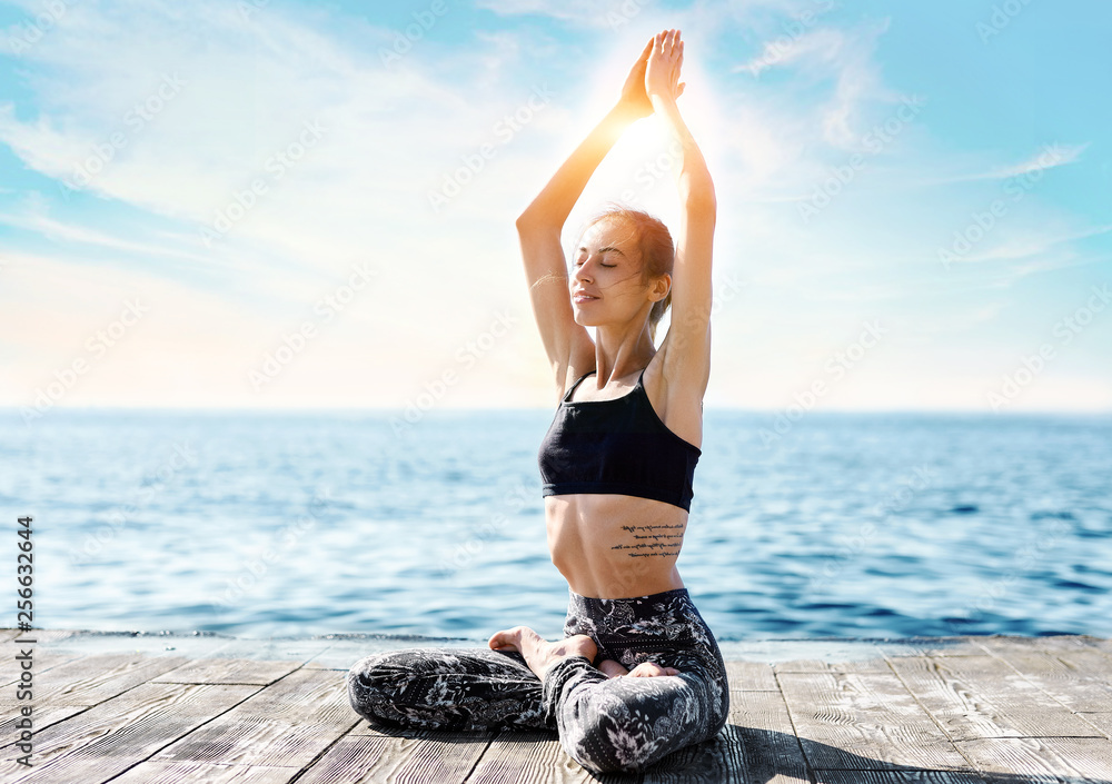 Beautiful young woman sitting in lotus pose with Raised Arms at the ...