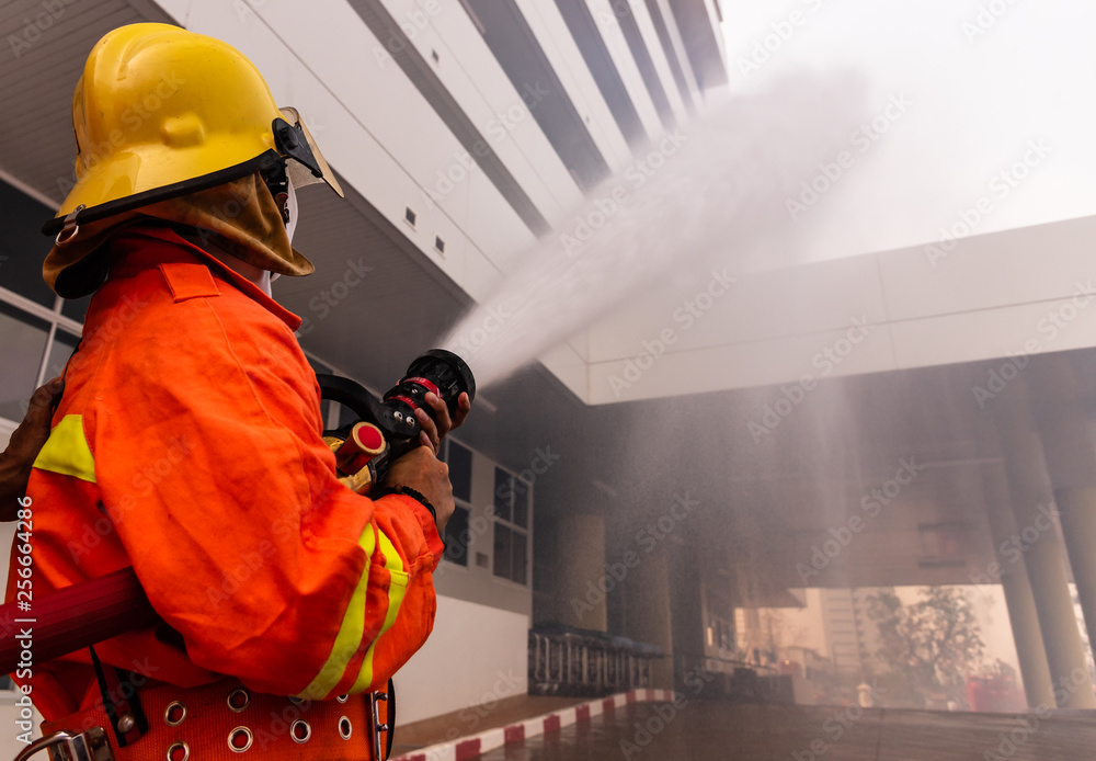 Firefighter hand holding water hose and water spraying to prevent high ...