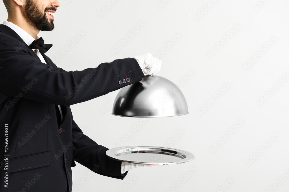 Waiter with tray and cloche on light background Stock Photo | Adobe Stock